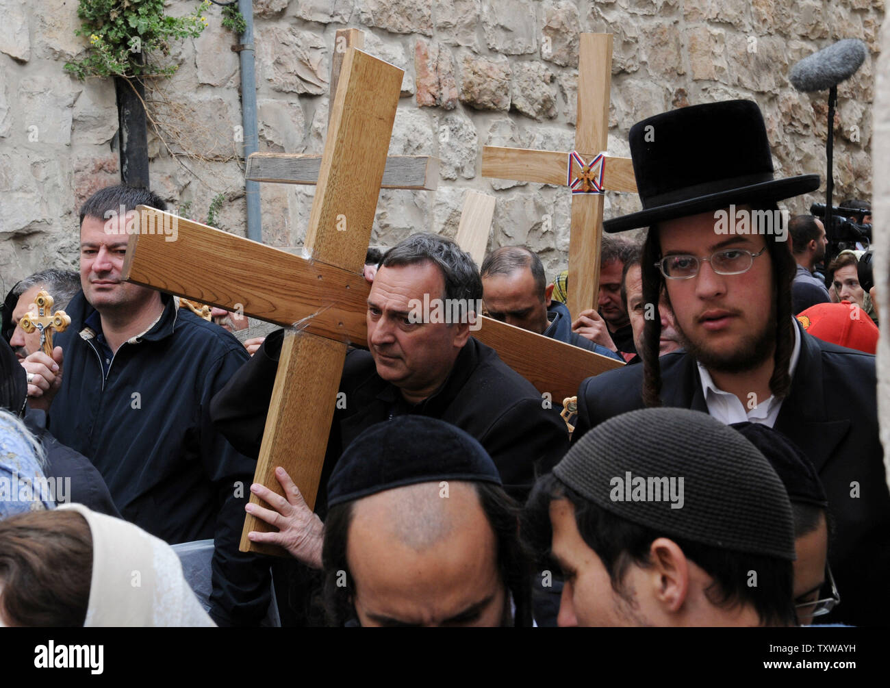 An Ultra-Orthodox Jew walks by Christian pilgrims carrying crosses on ...