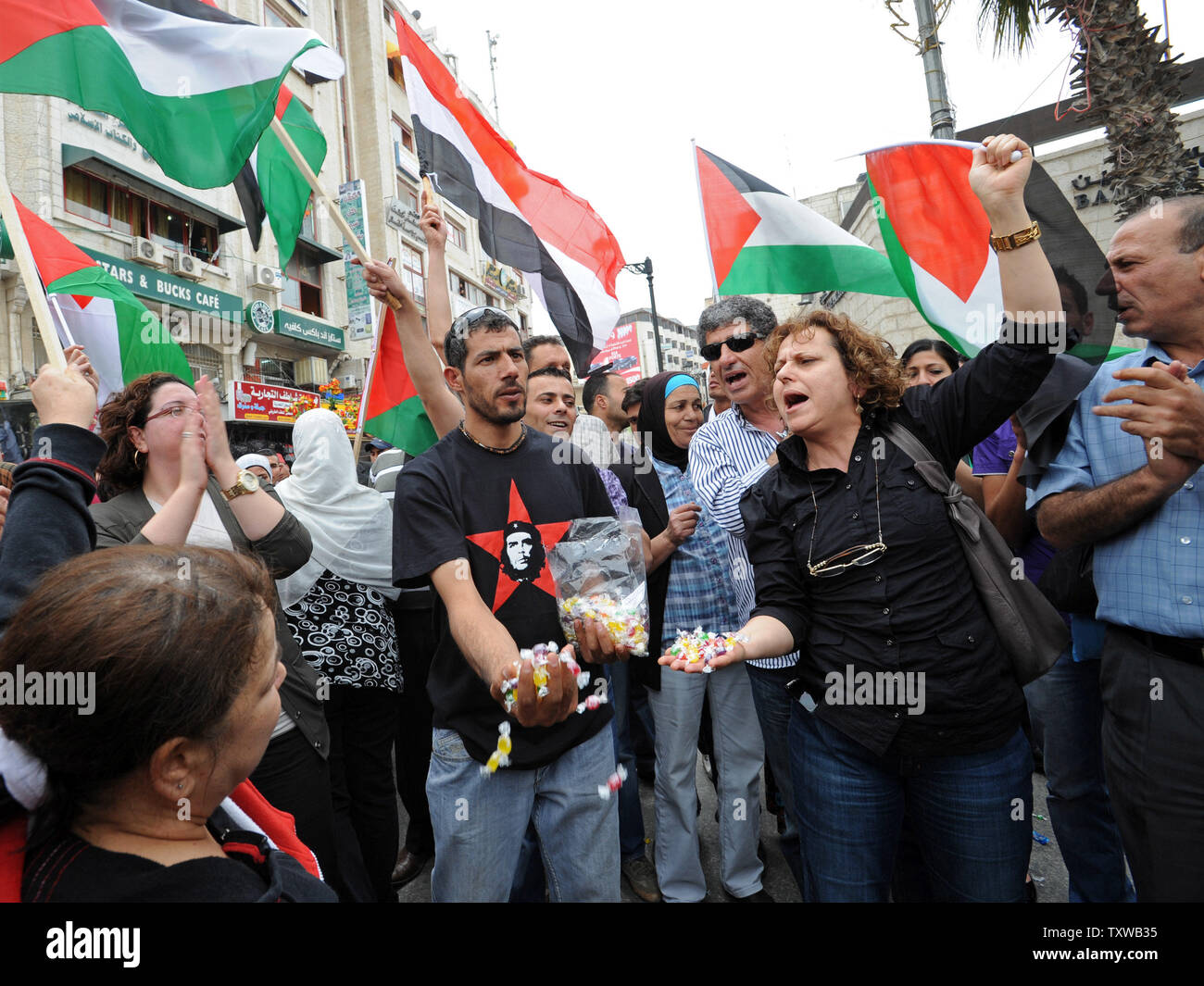 Palestinians hand out candy during a rally in Ramallah, West Bank, to ...