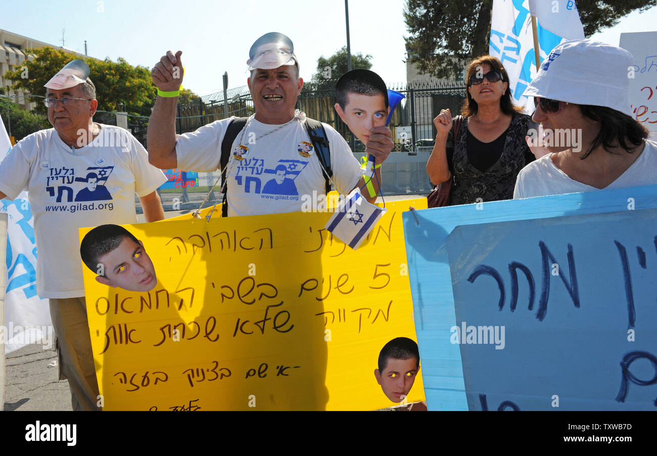 An Israeli holds a mask with the image of captured Israeli soldier ...