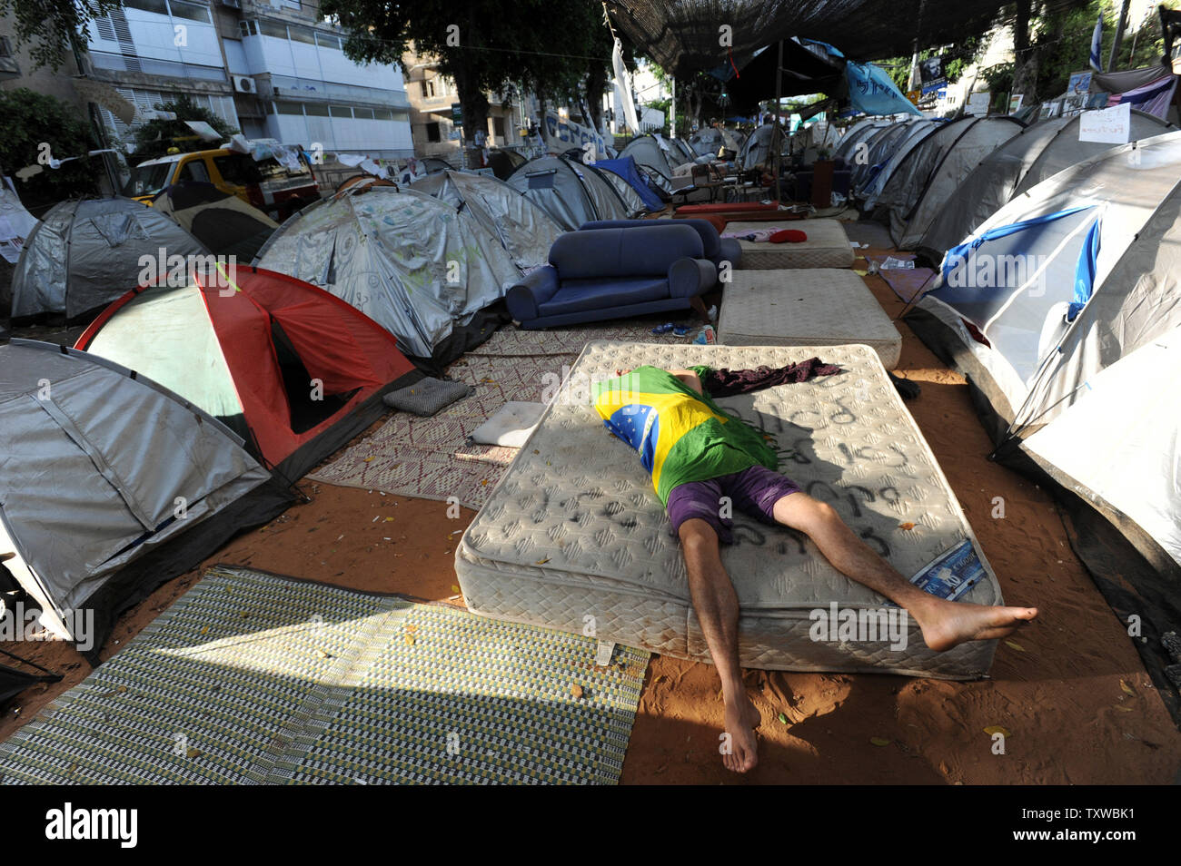 An Israeli sleeps in a protest tent encampment against the high costs ...