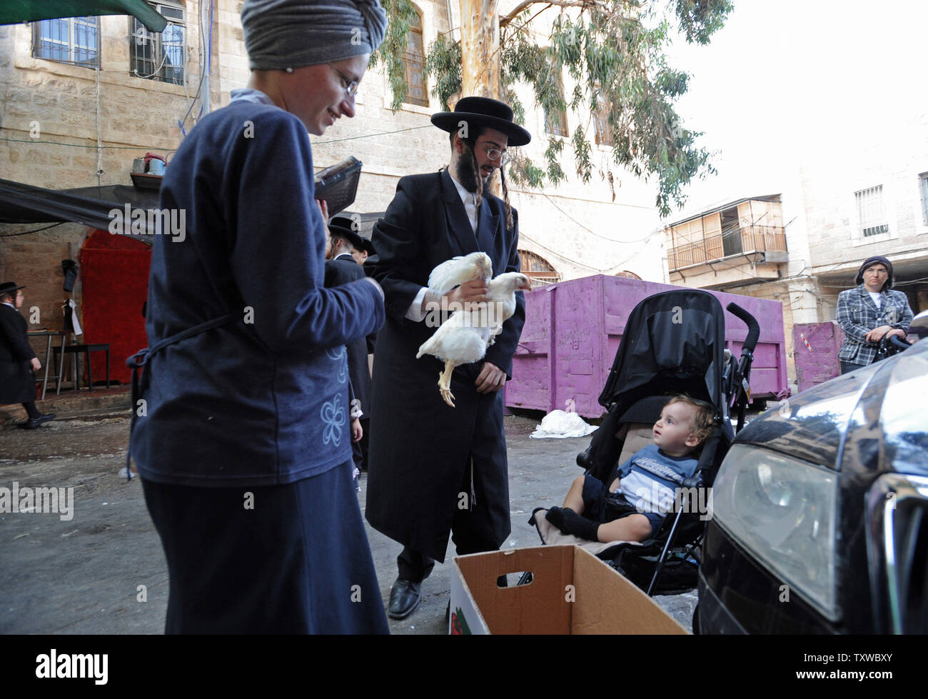 An Ultra-Orthodox Jewish man swings a chicken near a baby during the ...