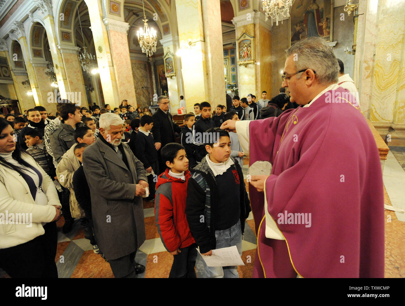 A Catholic priest sprinkles ashes on the head of a youth during an Ash ...