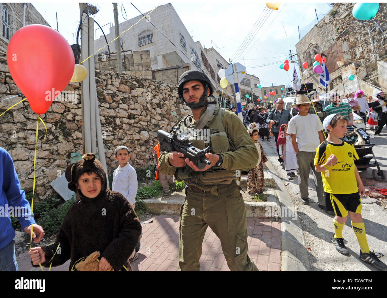 An Israeli soldier guards Jewish settlers, in costumes, during the ...