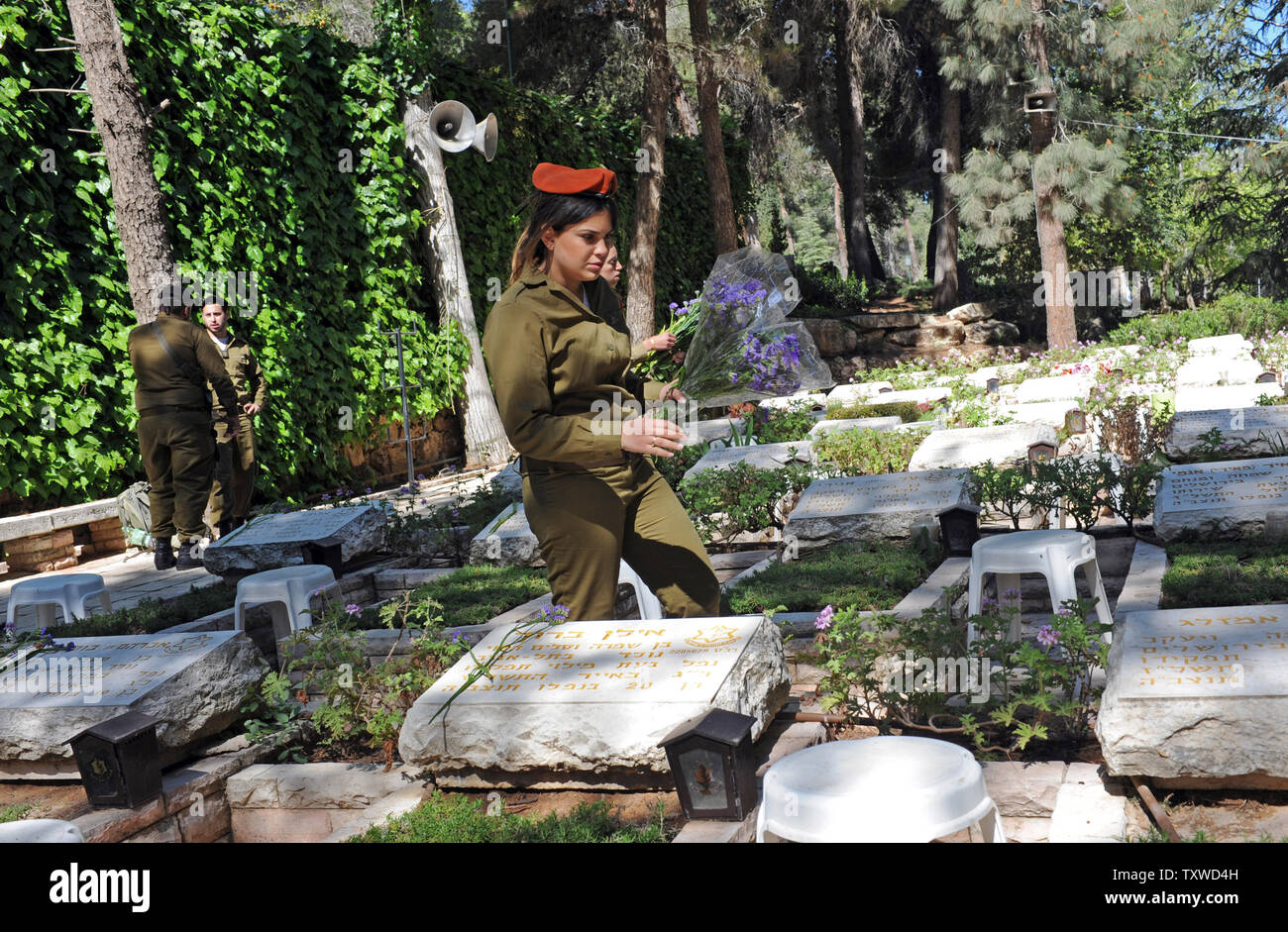 Israeli soldiers place flowers on the graves of fallen soldiers in the ...