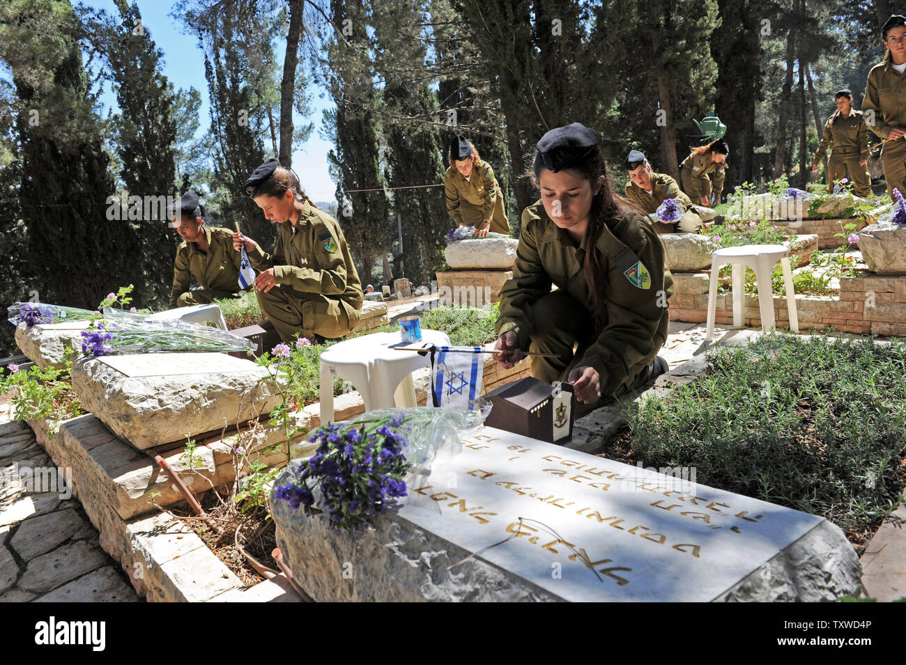 Israeli soldiers place small national flags and flowers on the graves ...