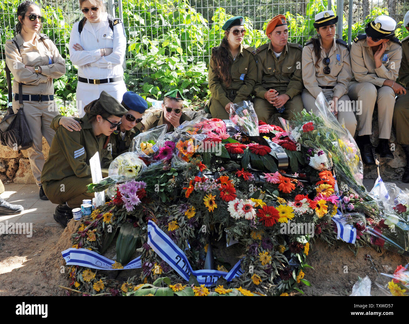 Israeli soldiers sit by the fresh grave of a fallen soldier on Memorial ...