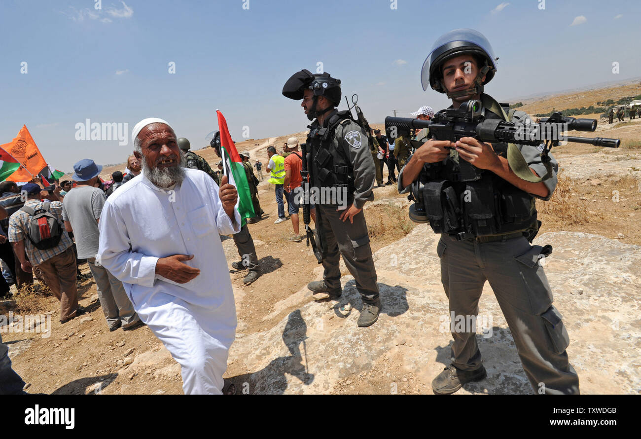 A Palestinian walks by Israeli border police lduring a demonstration in ...
