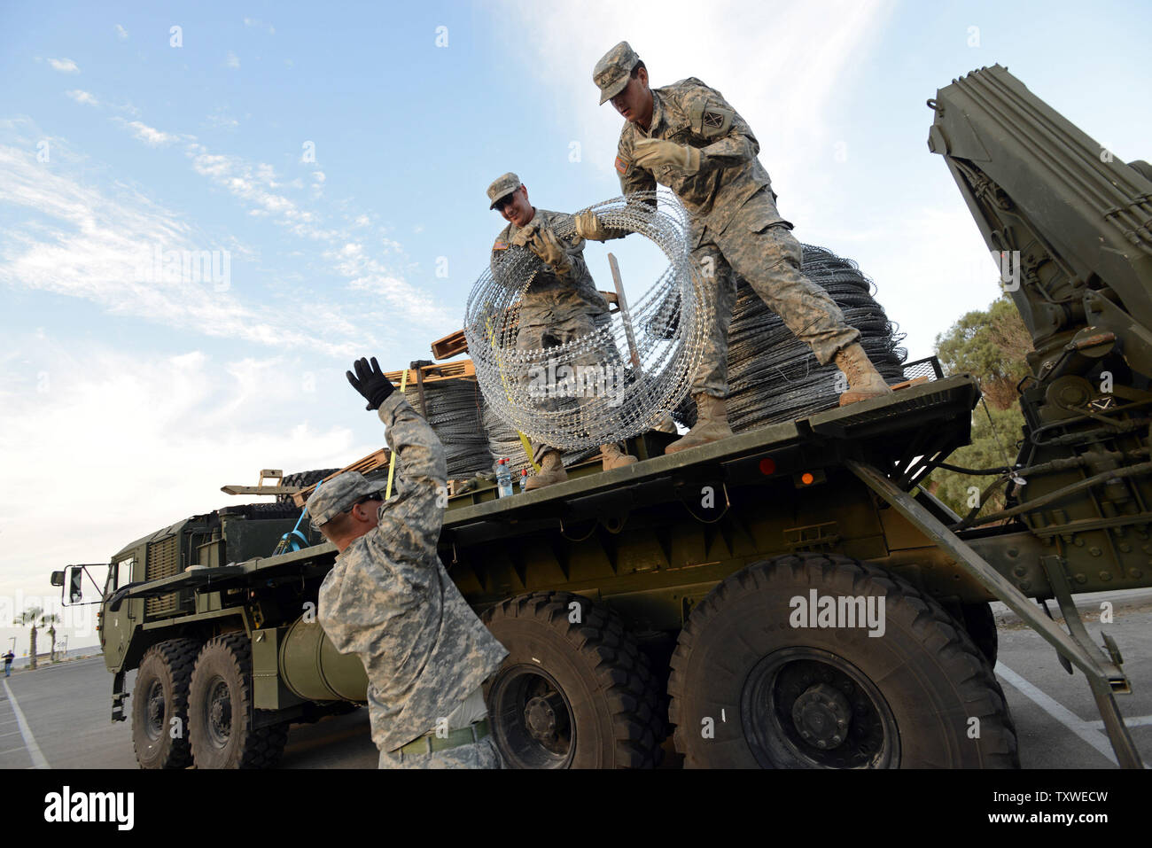 US soldiers gather coils of razor wire that surrounded their Patriot ...