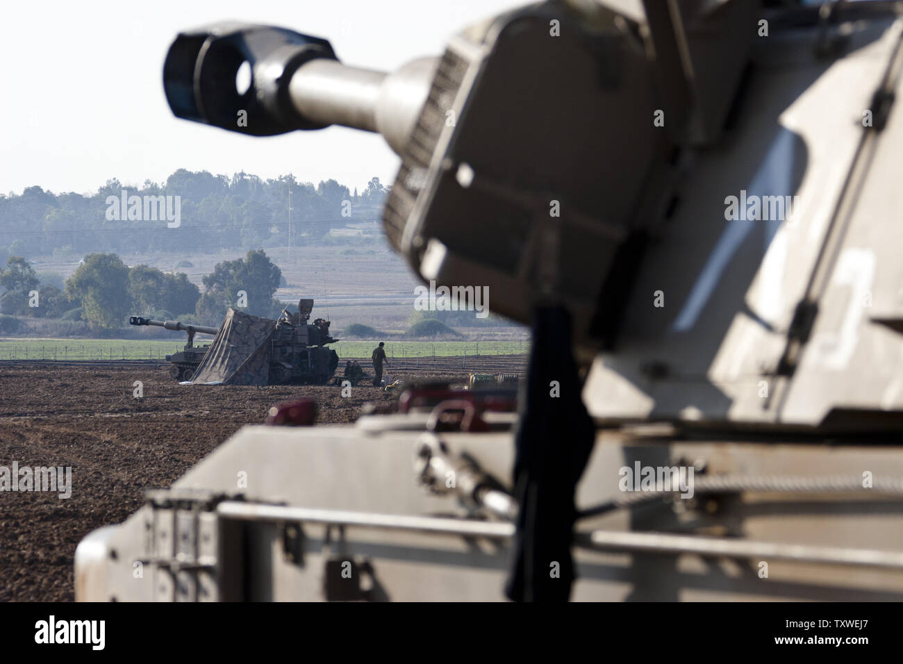 Israeli army artillery pieces are positioned in an agricultural field ...