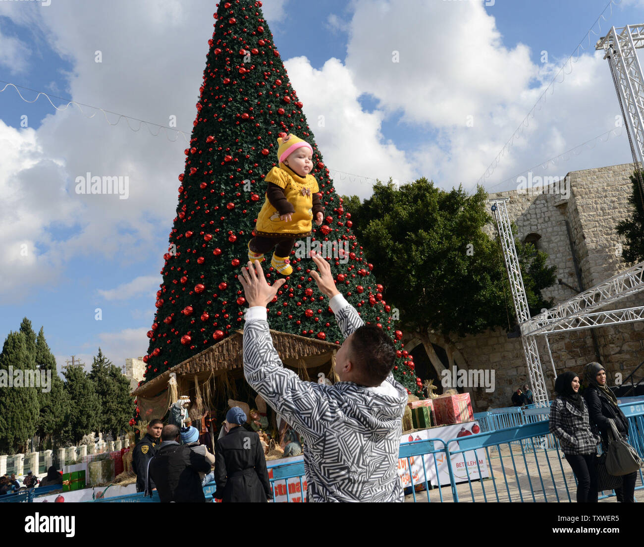 A Palestinian man throws his baby in the air in front of the Christmas ...