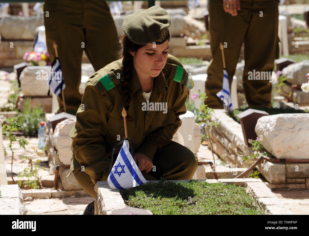 An Israeli soldiers places a national flag with a black ribbon on the ...