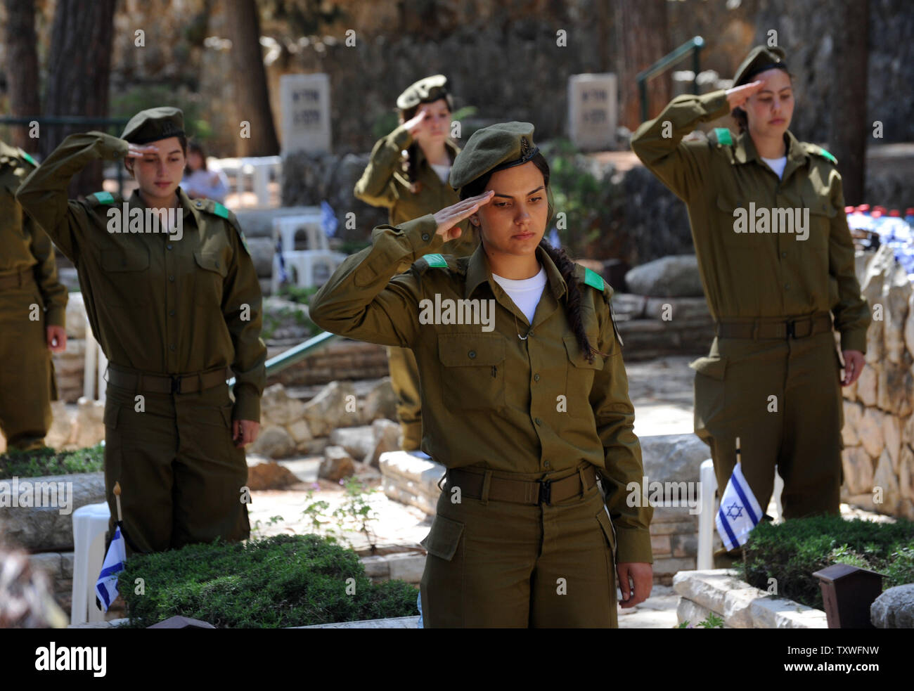 Israeli soldiers salute after decorating graves of fallen soldiers with ...
