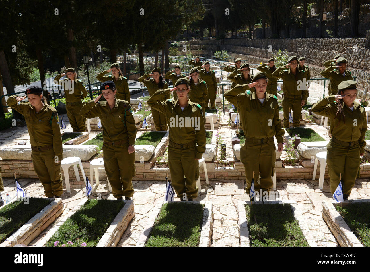 Israeli soldiers salute after decorating graves of fallen soldiers with ...