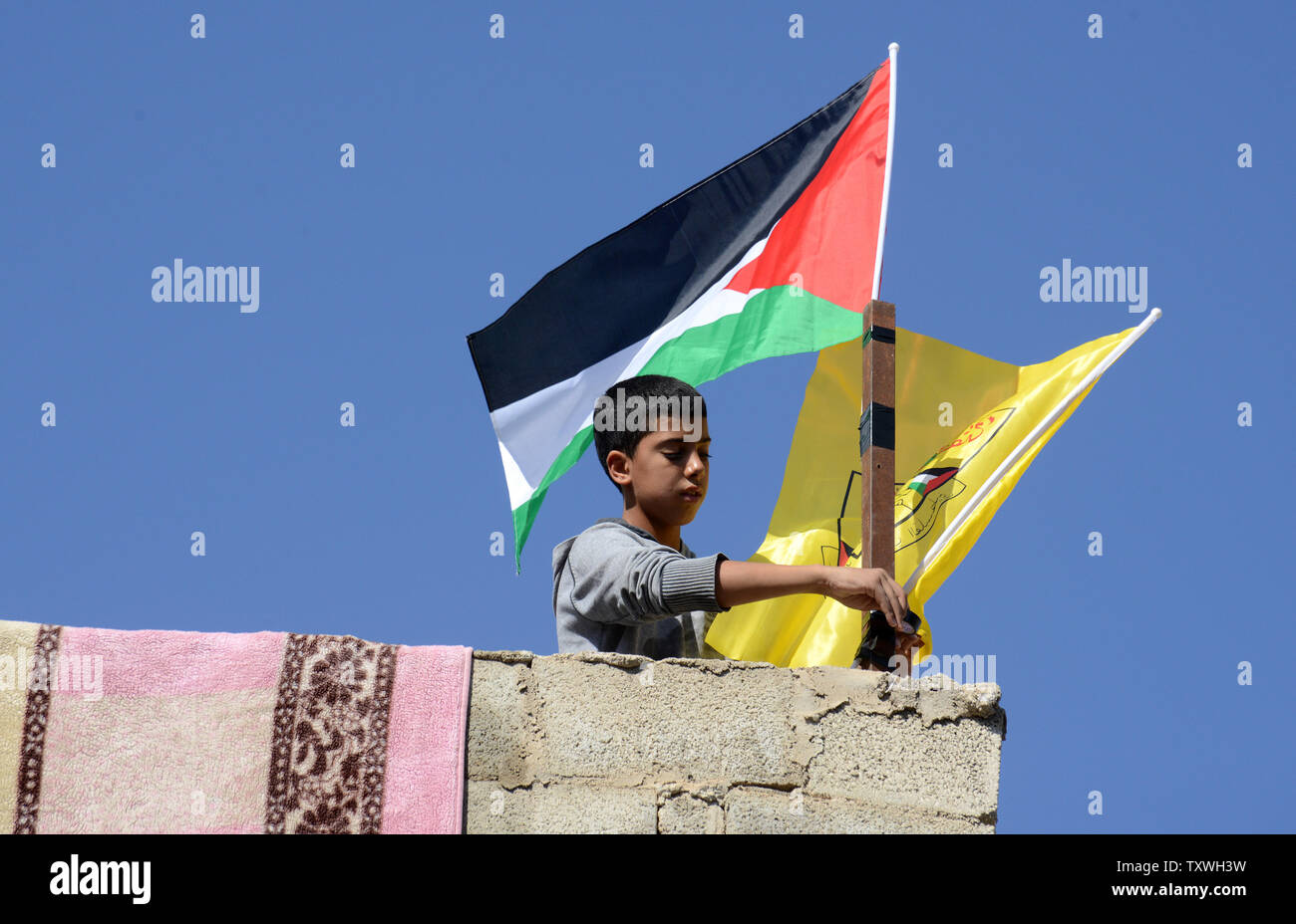 A boy secures a Palestinian flag to the roof of the house of ...