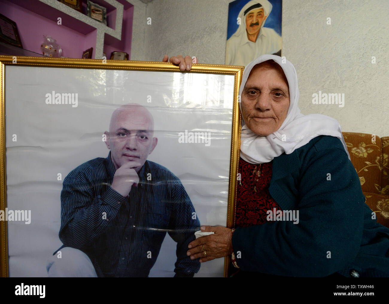 Amona Abed Rabbo, 75, sits next to a large portrait of her son ...