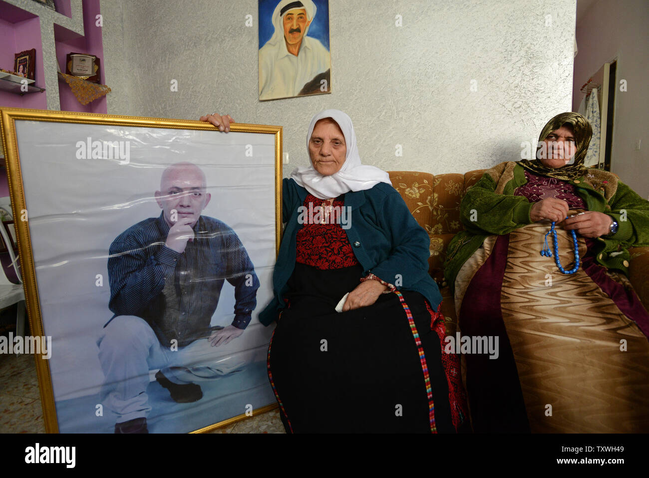 (L) Amona Abed Rabbo, 75, sits next to a large portrait of her son ...
