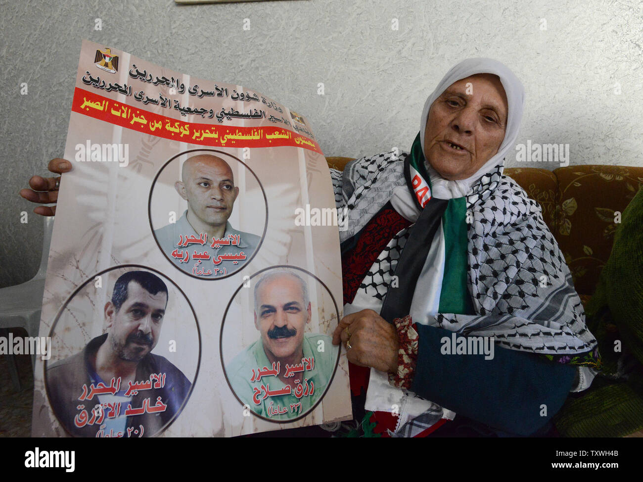 Amona Abed Rabbo, 75, holds a poster of Palestinian prisoners,her son ...