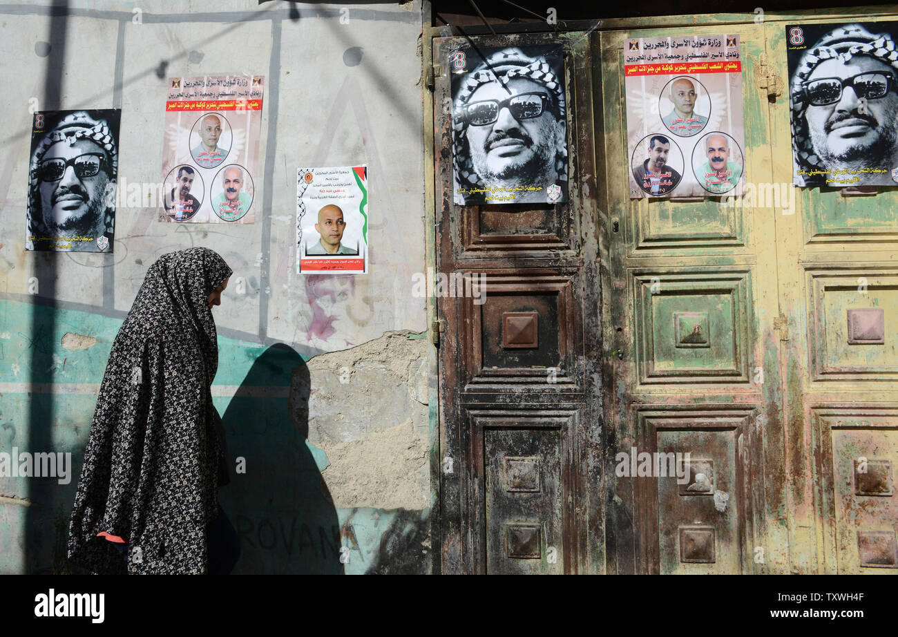 A Palestinian woman walks by posters of former Palestinian leader ...