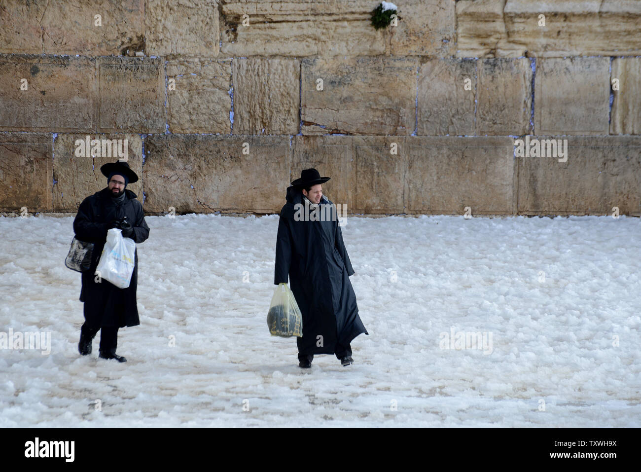 Ultra-Orthodox Israeli Jews walk in the snow at the Western Wall ...