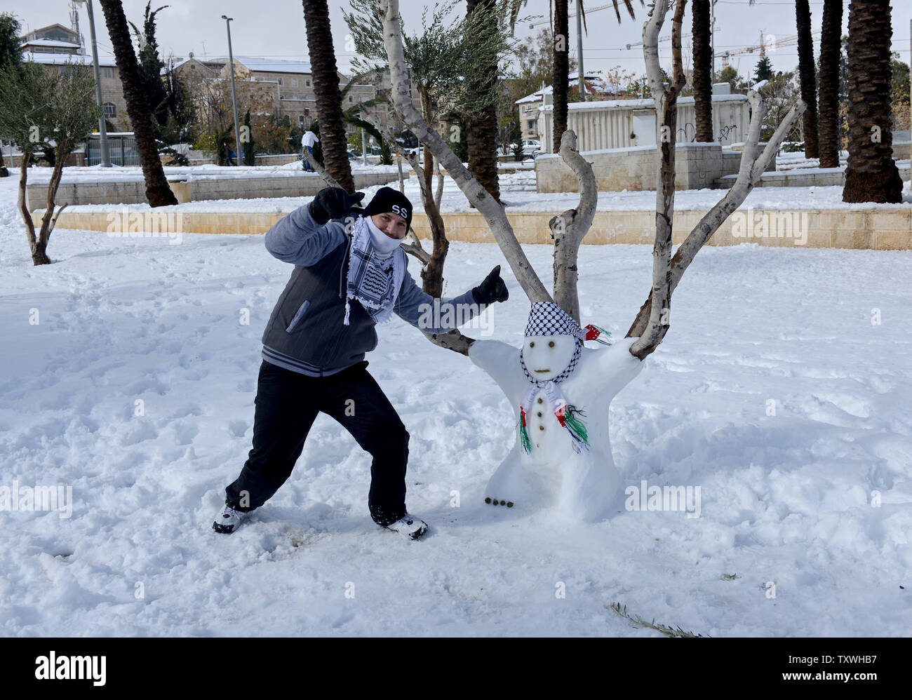 A Palestinian poses for a photo with a snowman outside the walls of the ...