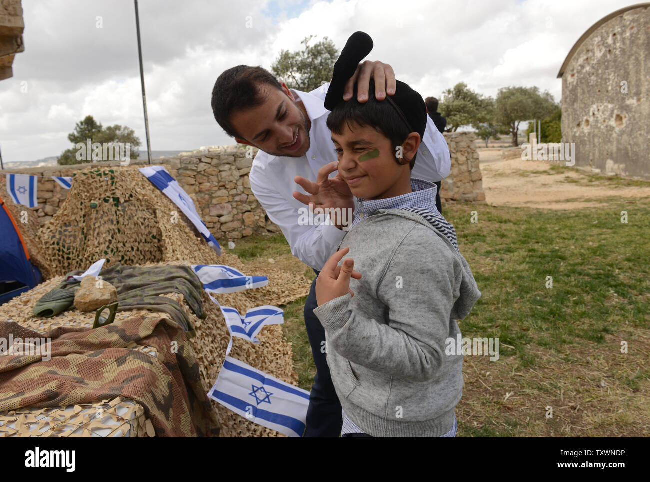 An Israeli puts camouflage paint on a boy's face at an Israeli army ...