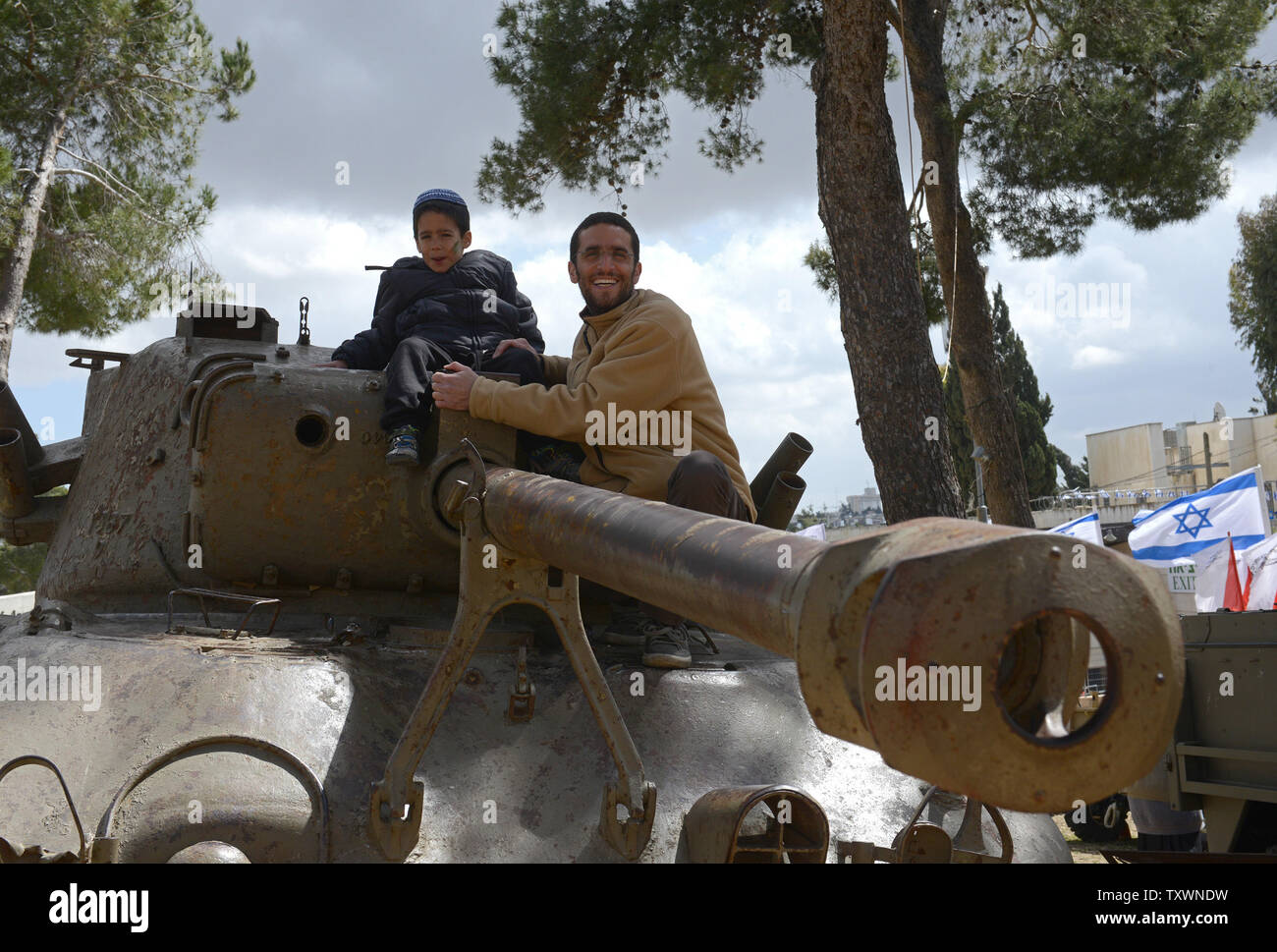 An Israeli man and his son sit on top of a Sherman tank at an Israeli ...