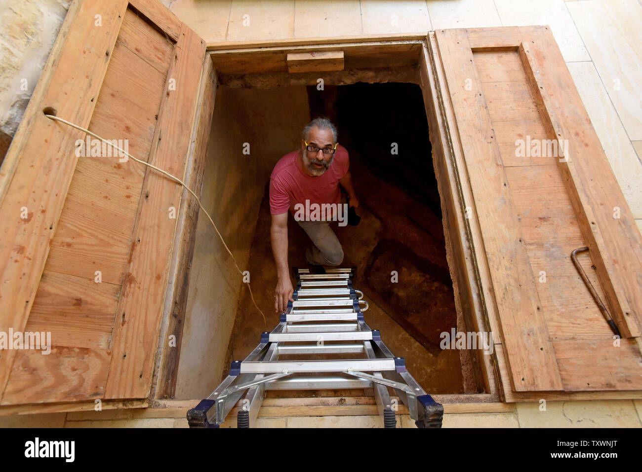 Tal, the owner of the house, descends on a ladder inside a wooden door ...