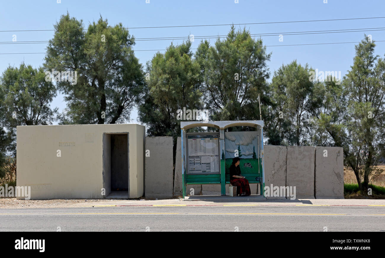 An Israeli woman waits for a bus in a station beside a bomb shelter and ...