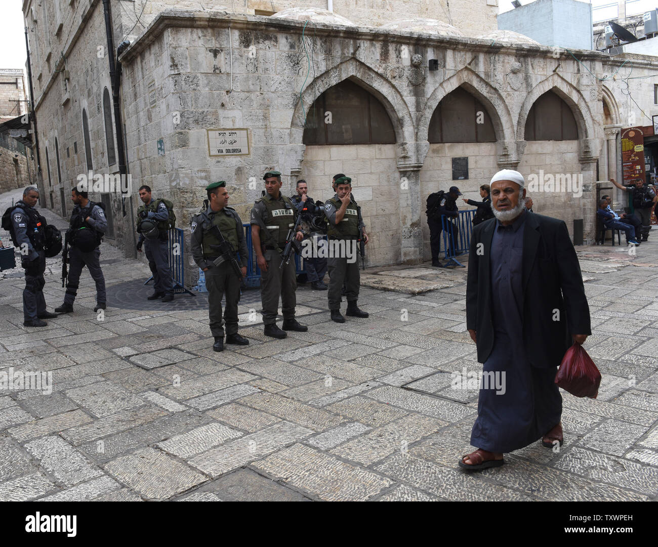 A Palestinian walks by Israeli border police on the Via Dolorosa, the ...