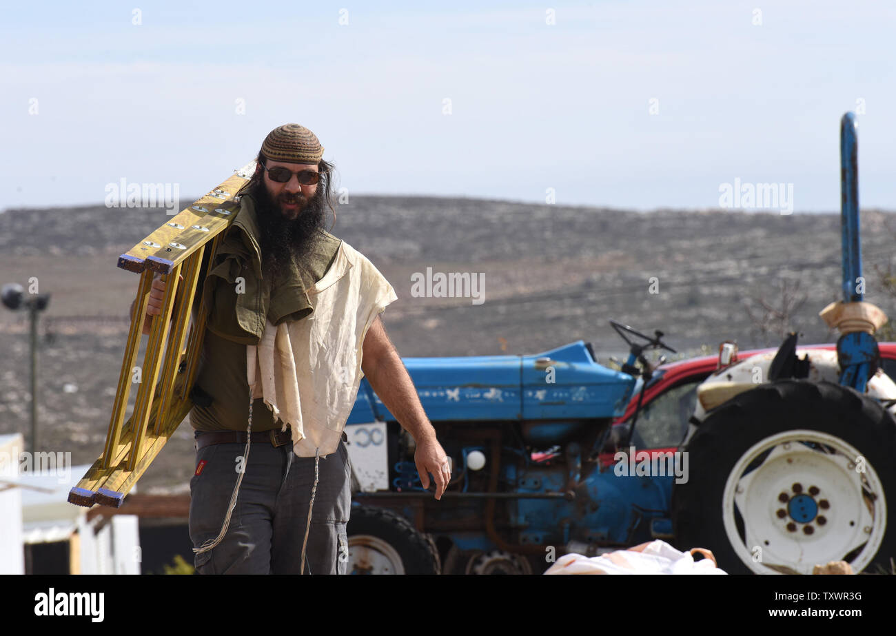 An Israeli settler carries a ladder in the Israeli illegal settlement ...