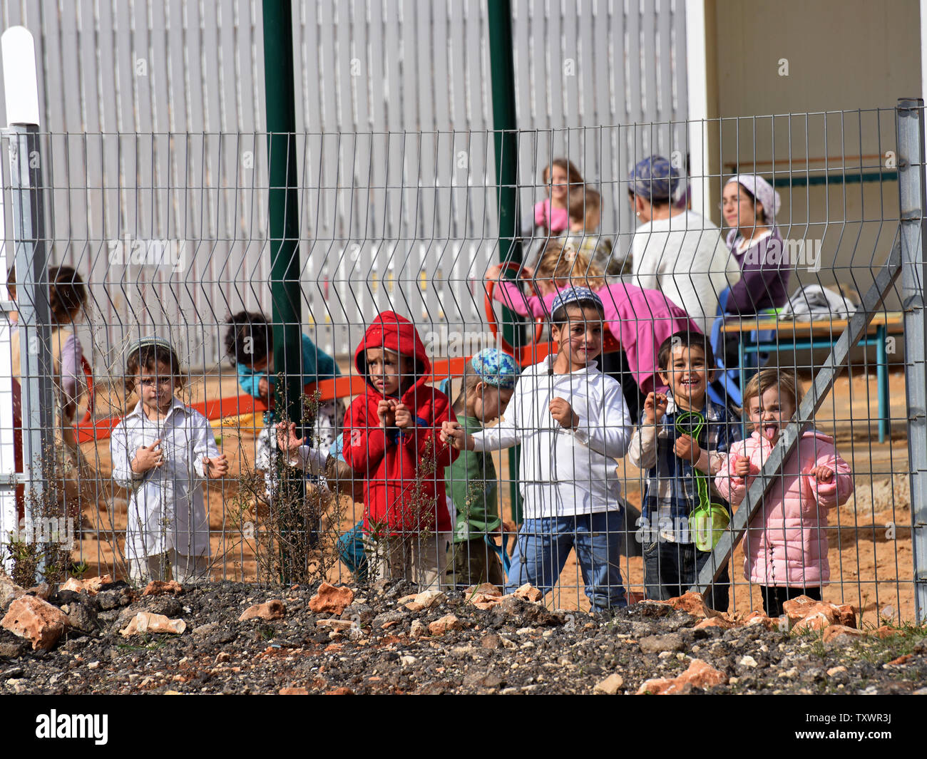 Israeli settler children play behind a fence in the Israeli illegal ...