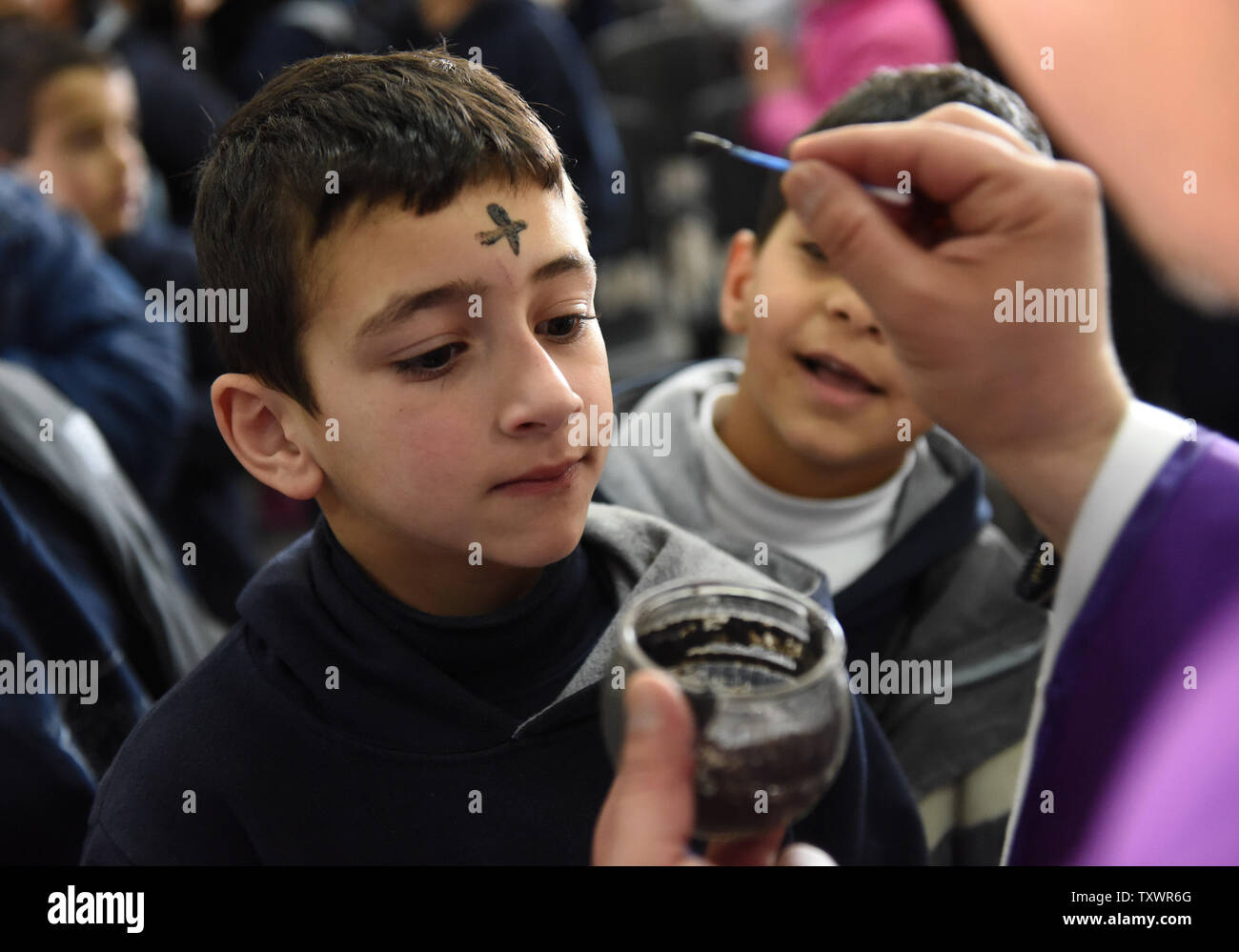 A Catholic priest places ashes on the forehead of a boy during mass on ...