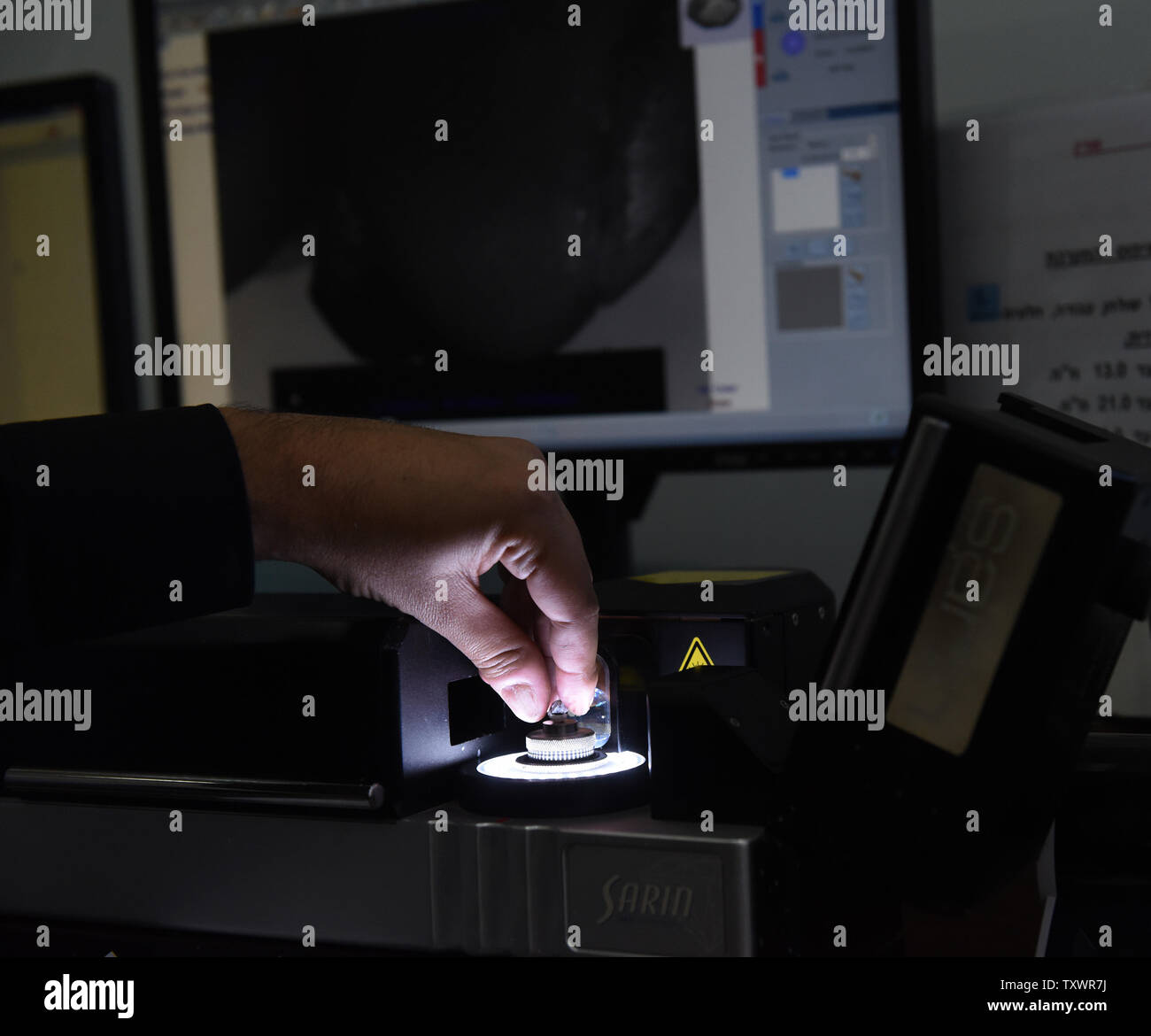 A diamond technician places a diamon in the Sarin machine to test the ...
