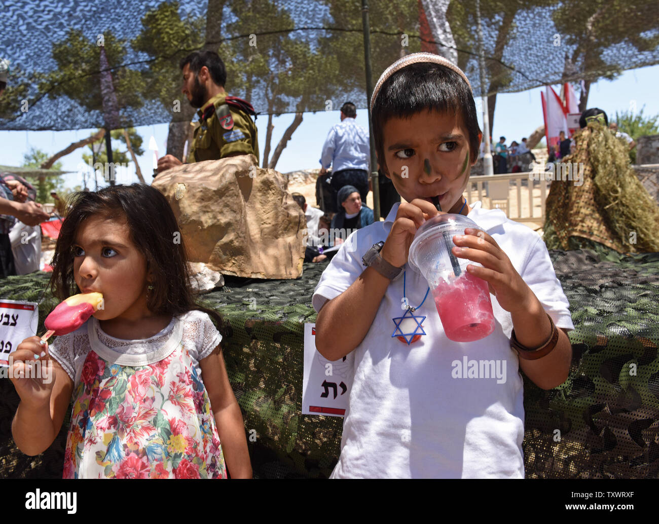 An Israeli boy wears camouflage paint on his face while enjoying a cold ...