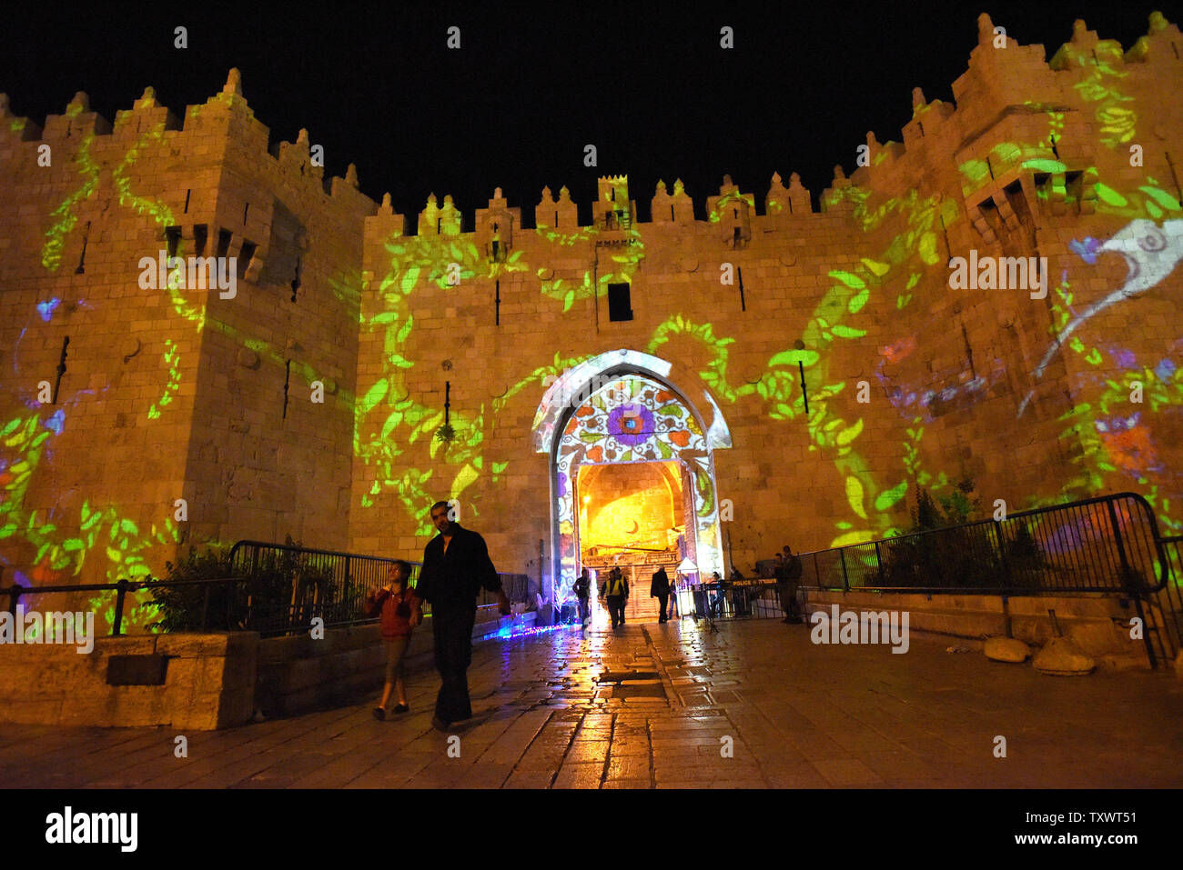 Palestinians walk under light scenes displayed on the Damascus Gate In ...