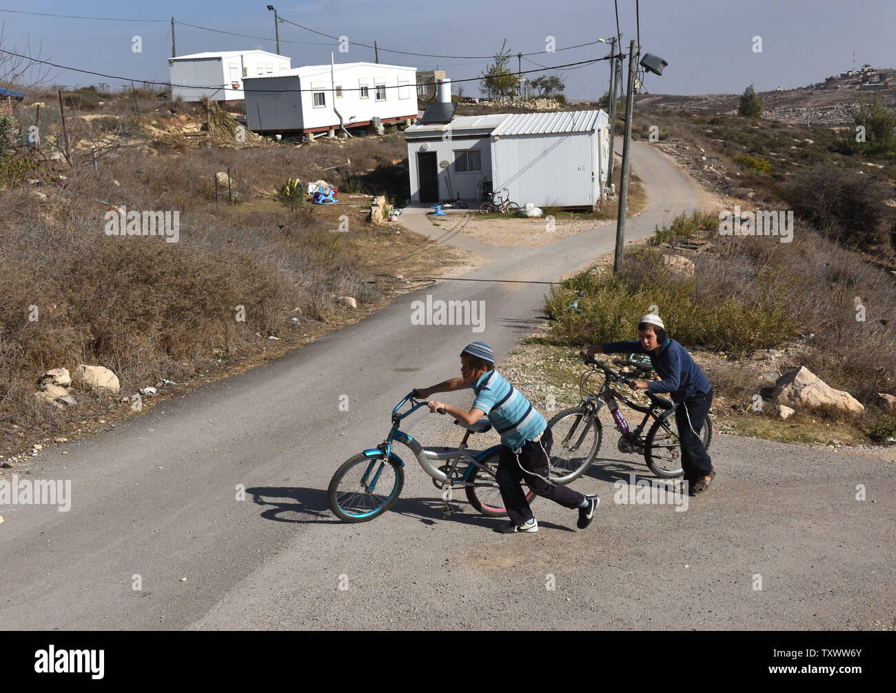 Jewish children push bicycles in the unauthorized Israeli settlement ...