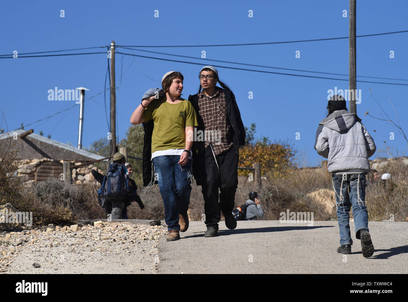 Jewish settlers walk in the unauthorized Israeli settlement outpost ...