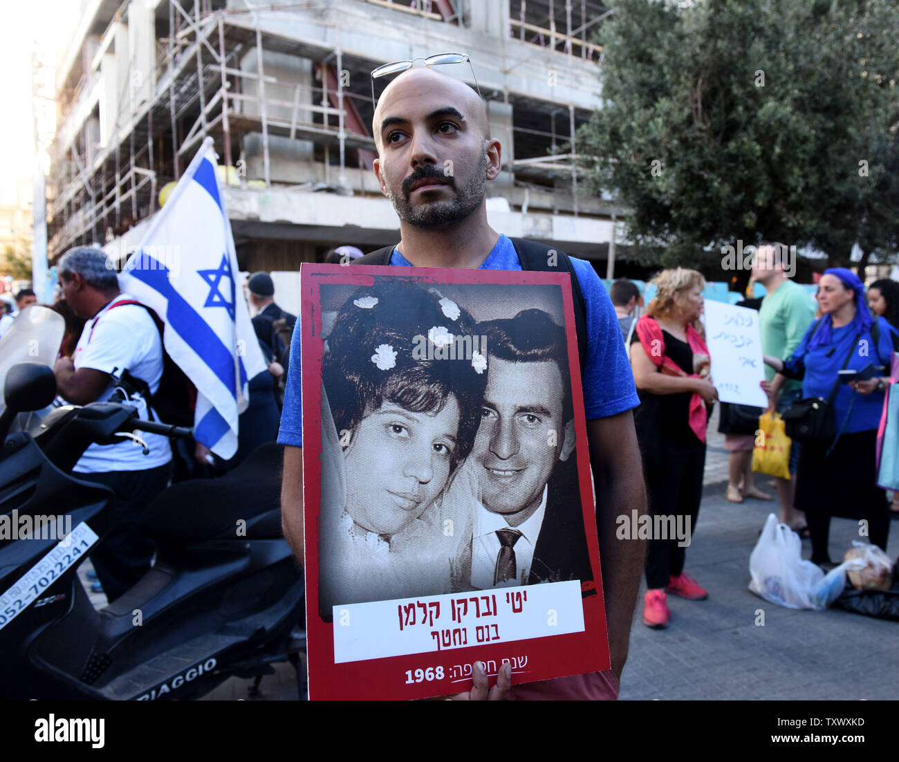 An Israeli holds a photo of a family whose children disappeared at a ...
