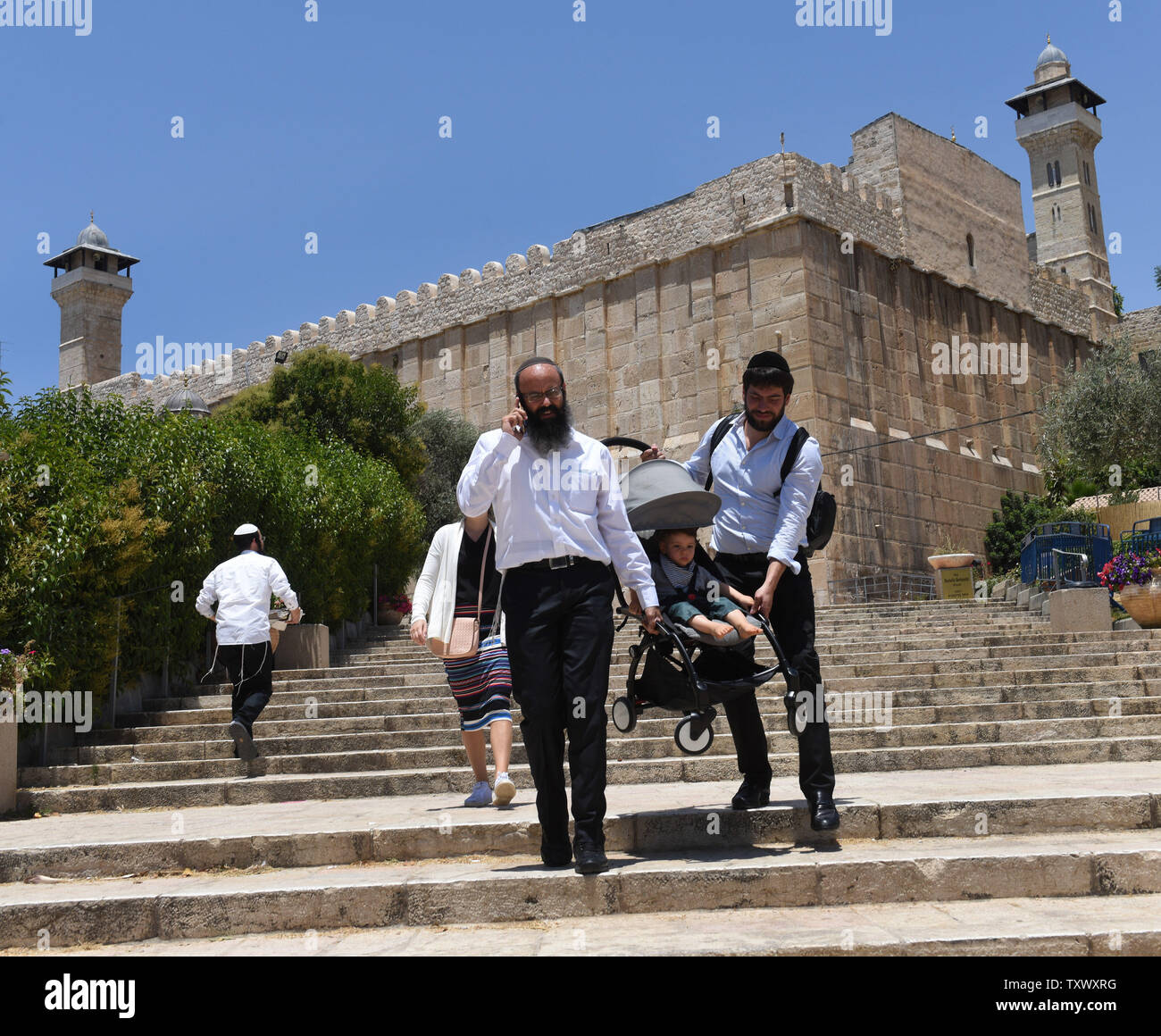 Orthodox Jews carry a baby in a carriage down the stairs from the Cave ...
