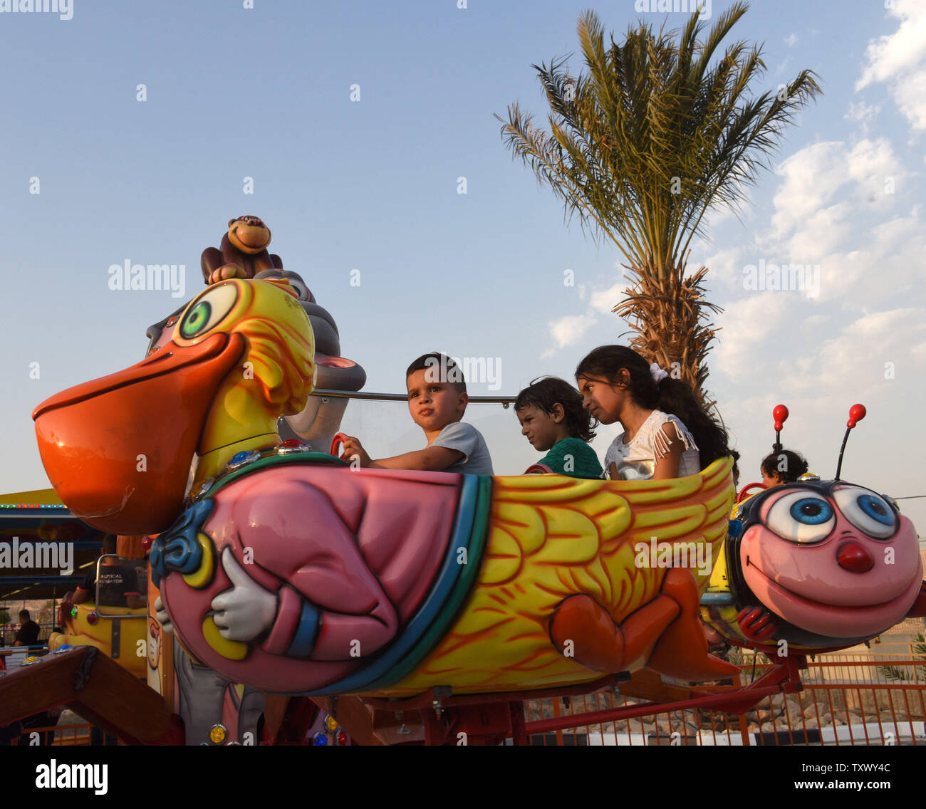 Palestinian children enjoy rides on the third day of the Muslim feast ...