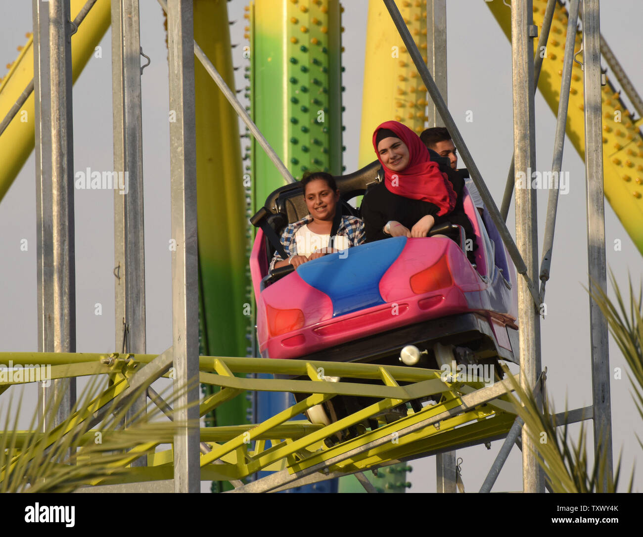 Palestinians ride a roller coaster on the third day of the Muslim feast ...