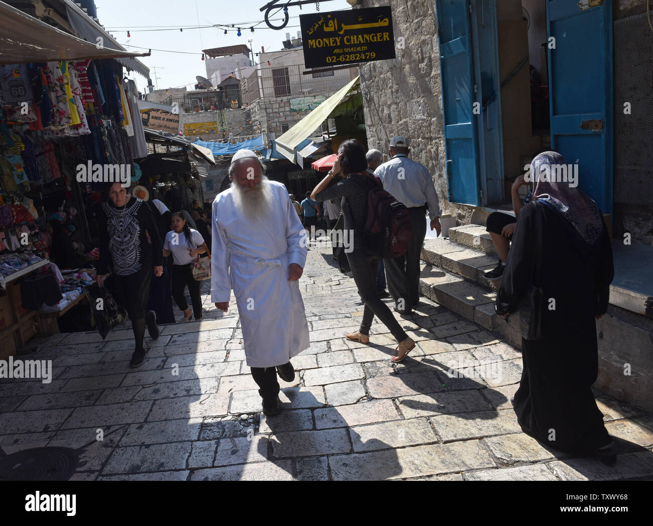 An Ultra-Orthodox Jew wears a white robe as he walks past a Muslim ...