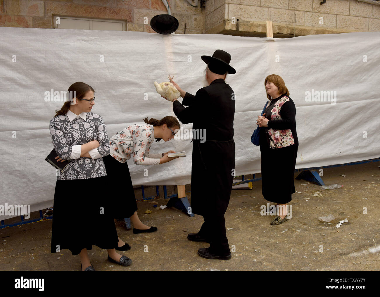 An Ultra-Orthodox Jew swings a chicken his daughter's head as part of ...