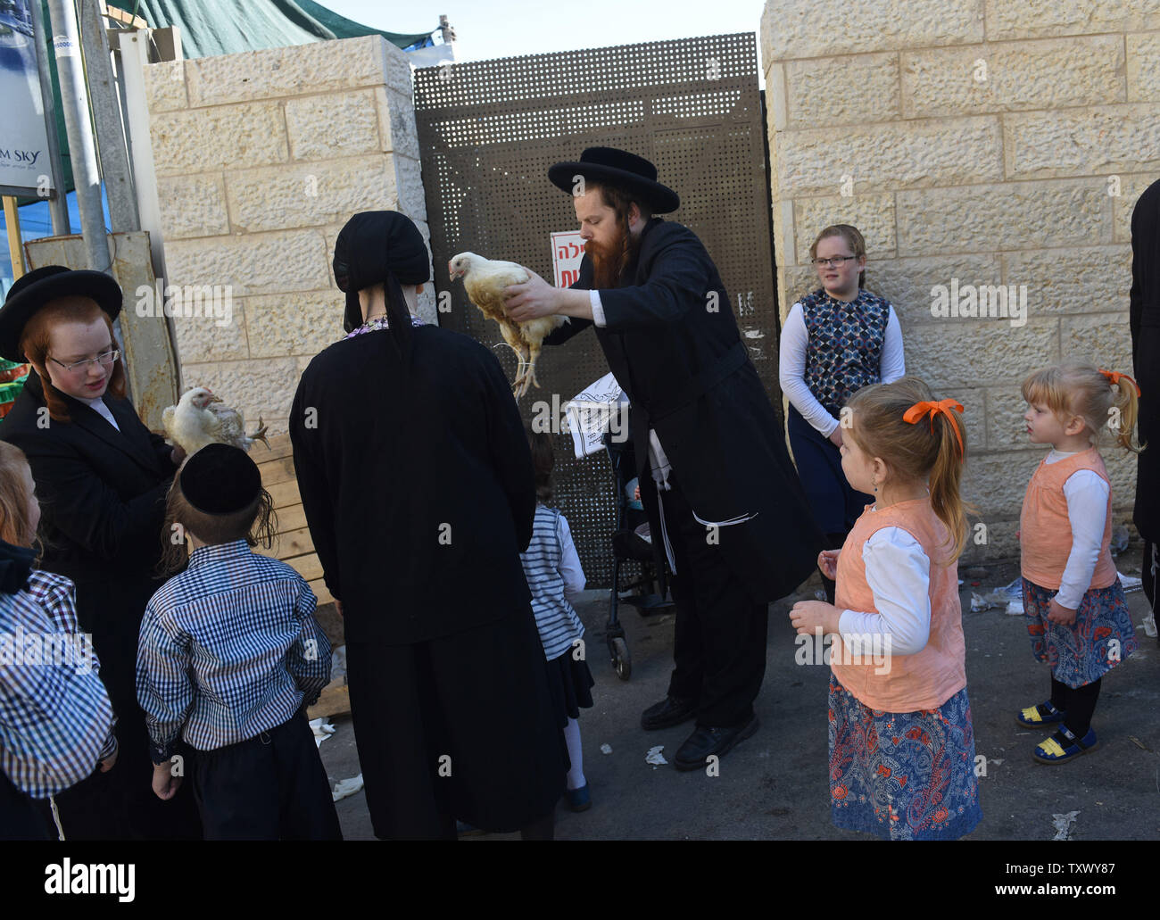 An Ultra-Orthodox Jew swings a chicken over his children as part of the ...