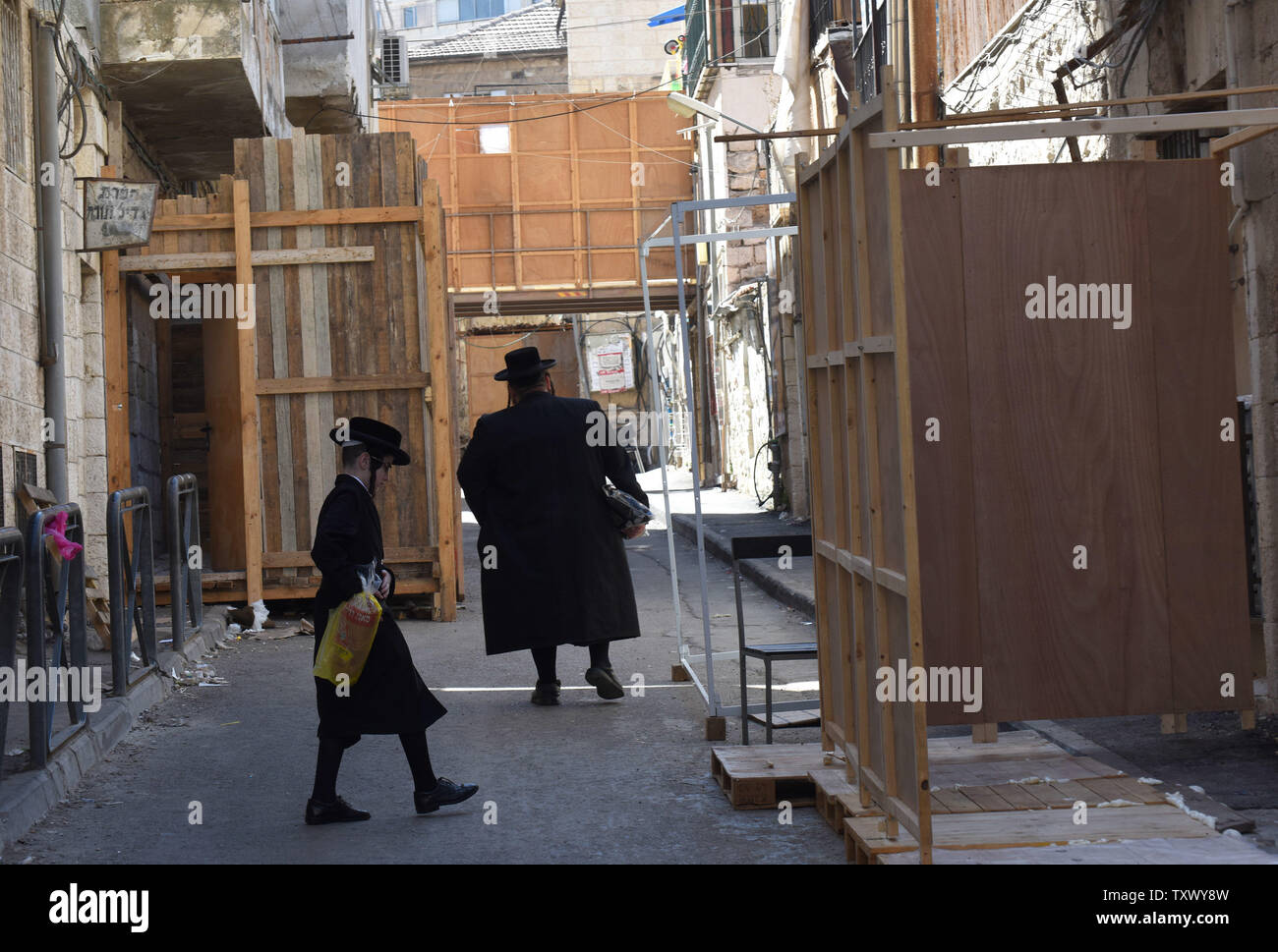 Ultra-Orthodox Jews walk on a street with wooden sukkahs, a temporary ...
