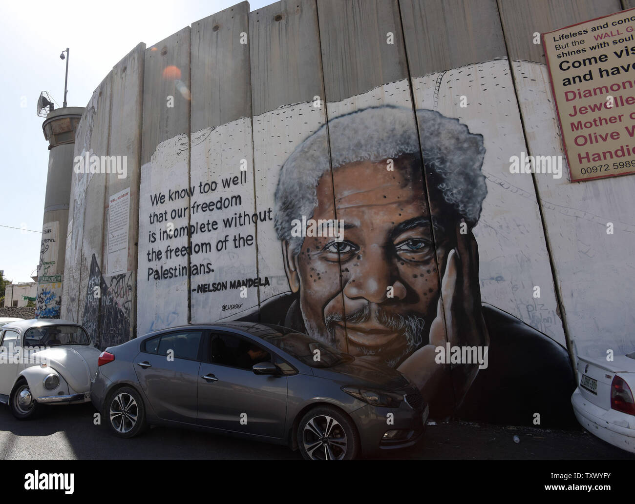 Palestinians stand in front of graffiti by Austrian artist LUSHSUX of ...