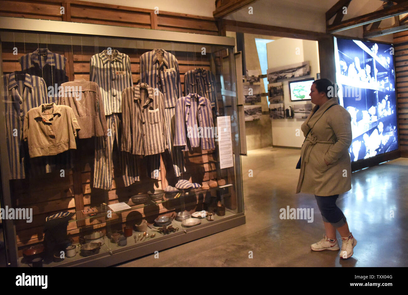 A woman views uniforms worn by Jews in concentration camps on display ...