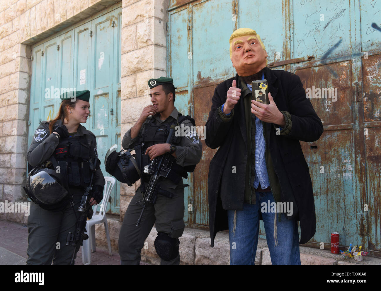 Israeli border police stand beside a settler wearing a mask of U.S ...