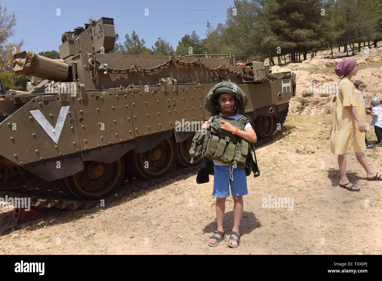 A Jewish boy wears army gear in front of a armored personnel carrier on ...