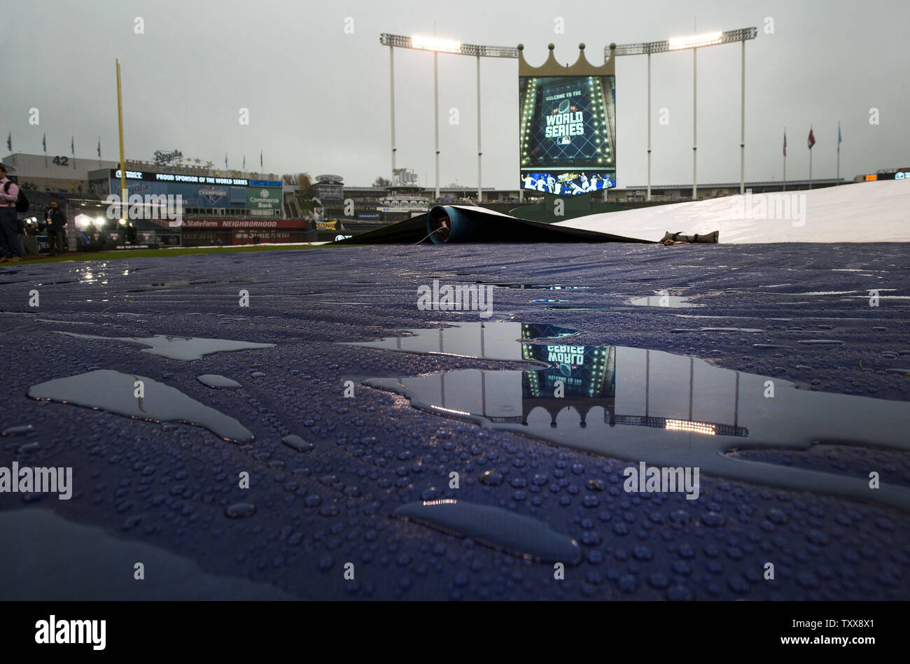 The scoreboard is seen reflected in a puddle as rain falls before game ...